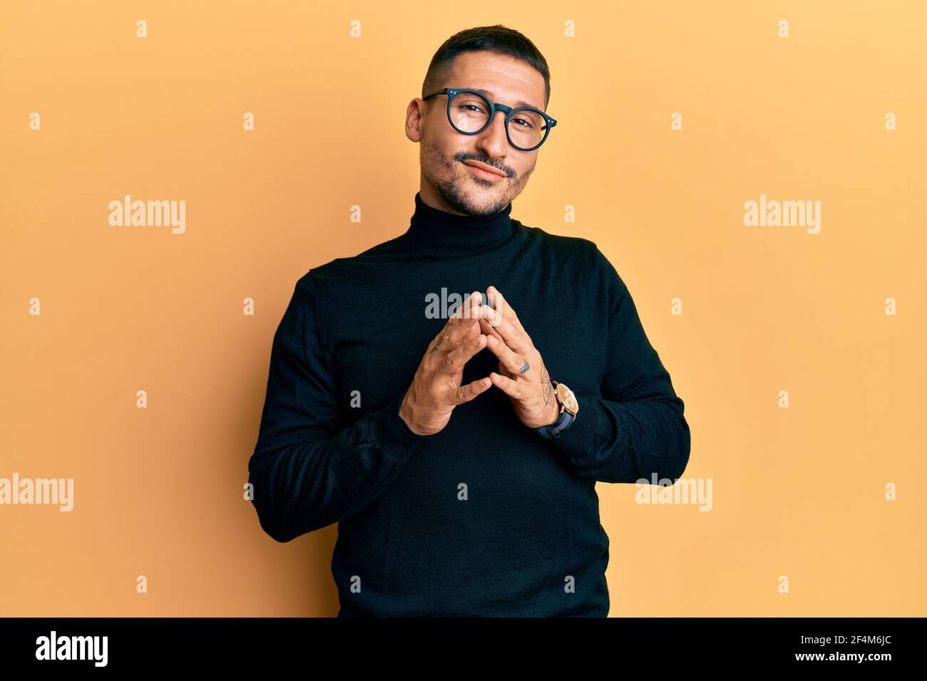 Handsome man with tattoos wearing turtleneck sweater and glasses hands ...