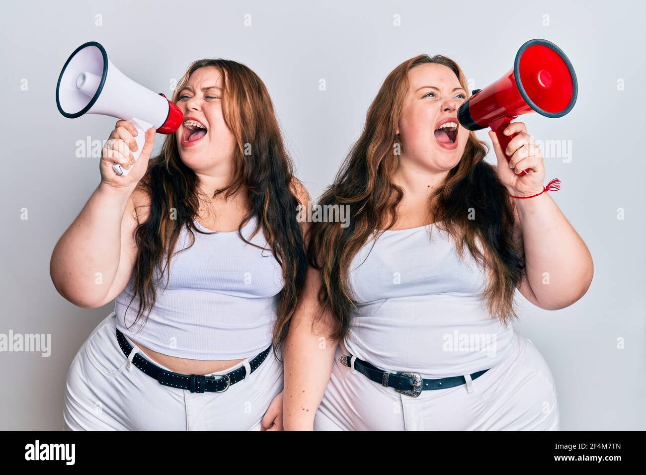 Plus size caucasian sisters woman shouting through megaphone angry and ...