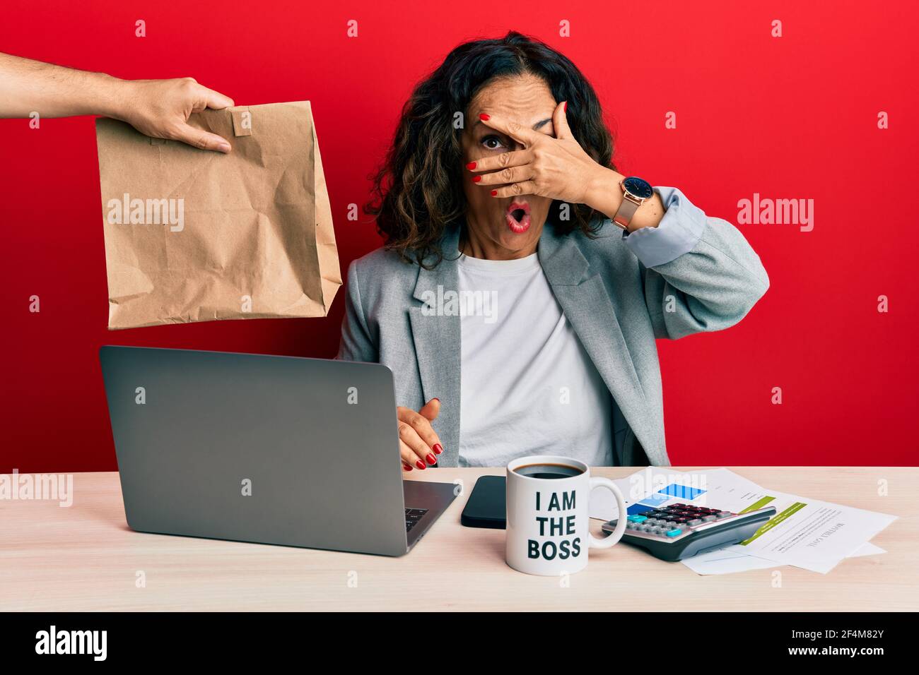 Beautiful middle age woman working at the office ordering delivery food ...
