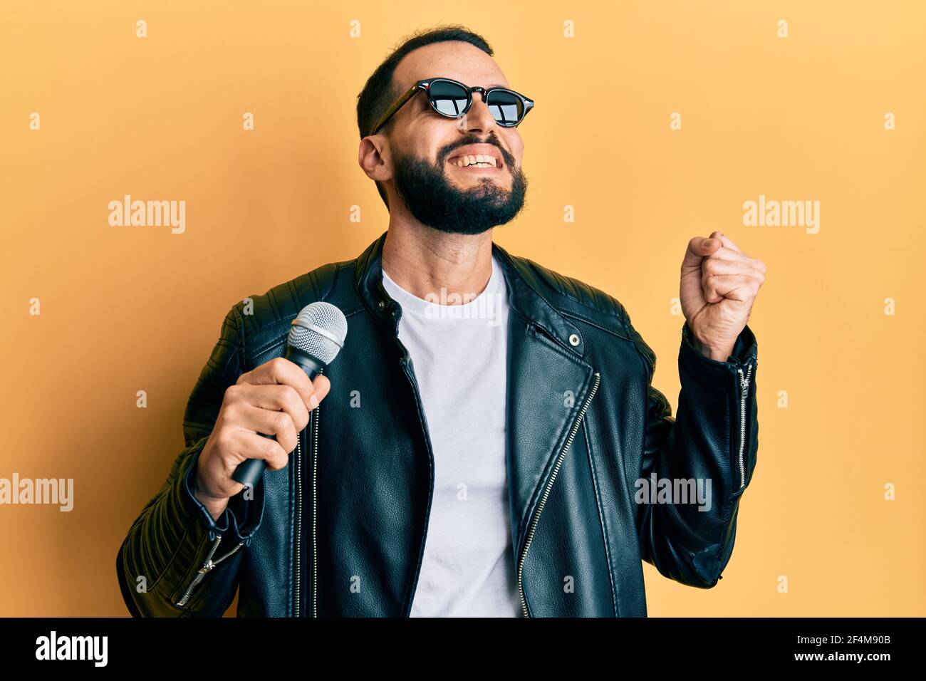 Young man with beard singing song using microphone screaming proud ...