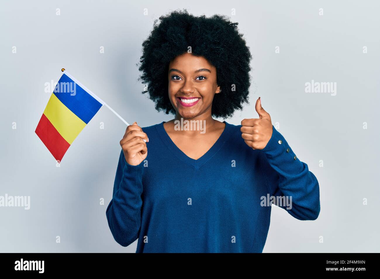 Young african american woman holding romania flag smiling happy and ...