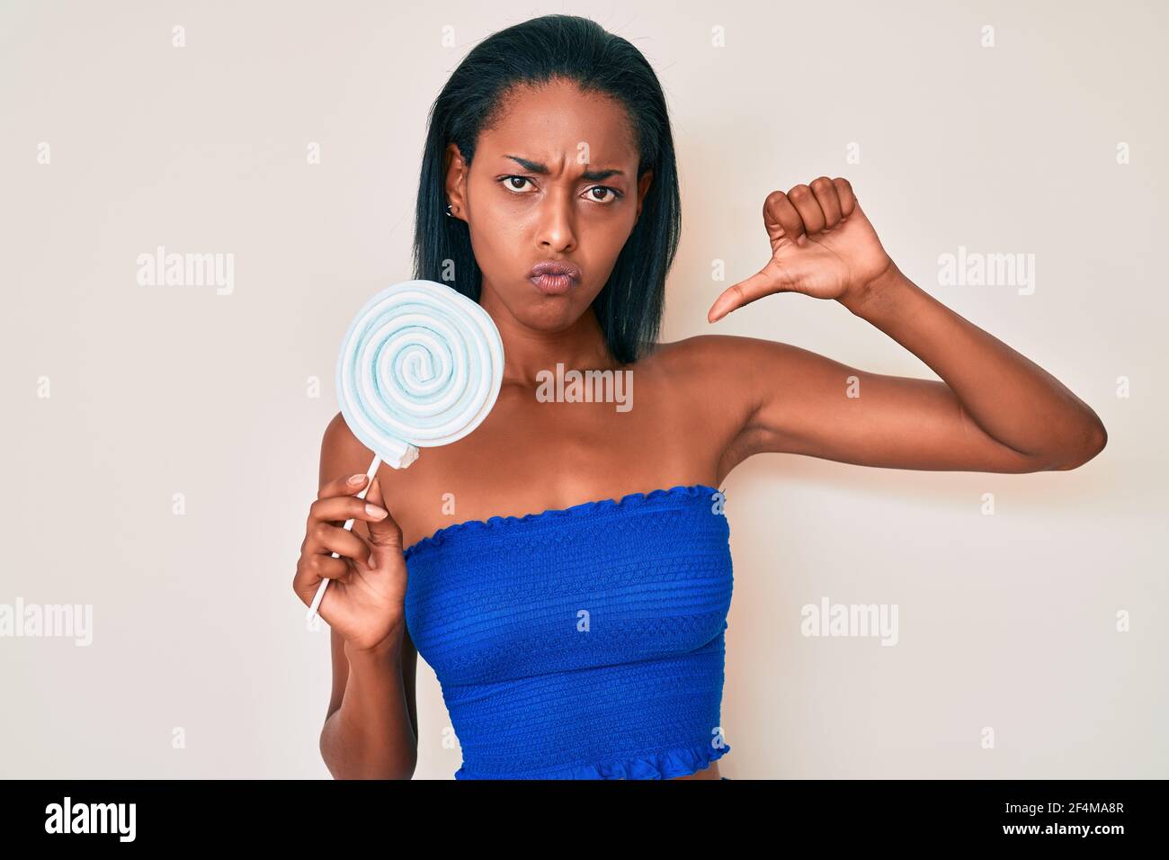 Young african american woman holding sugar candy with angry face ...