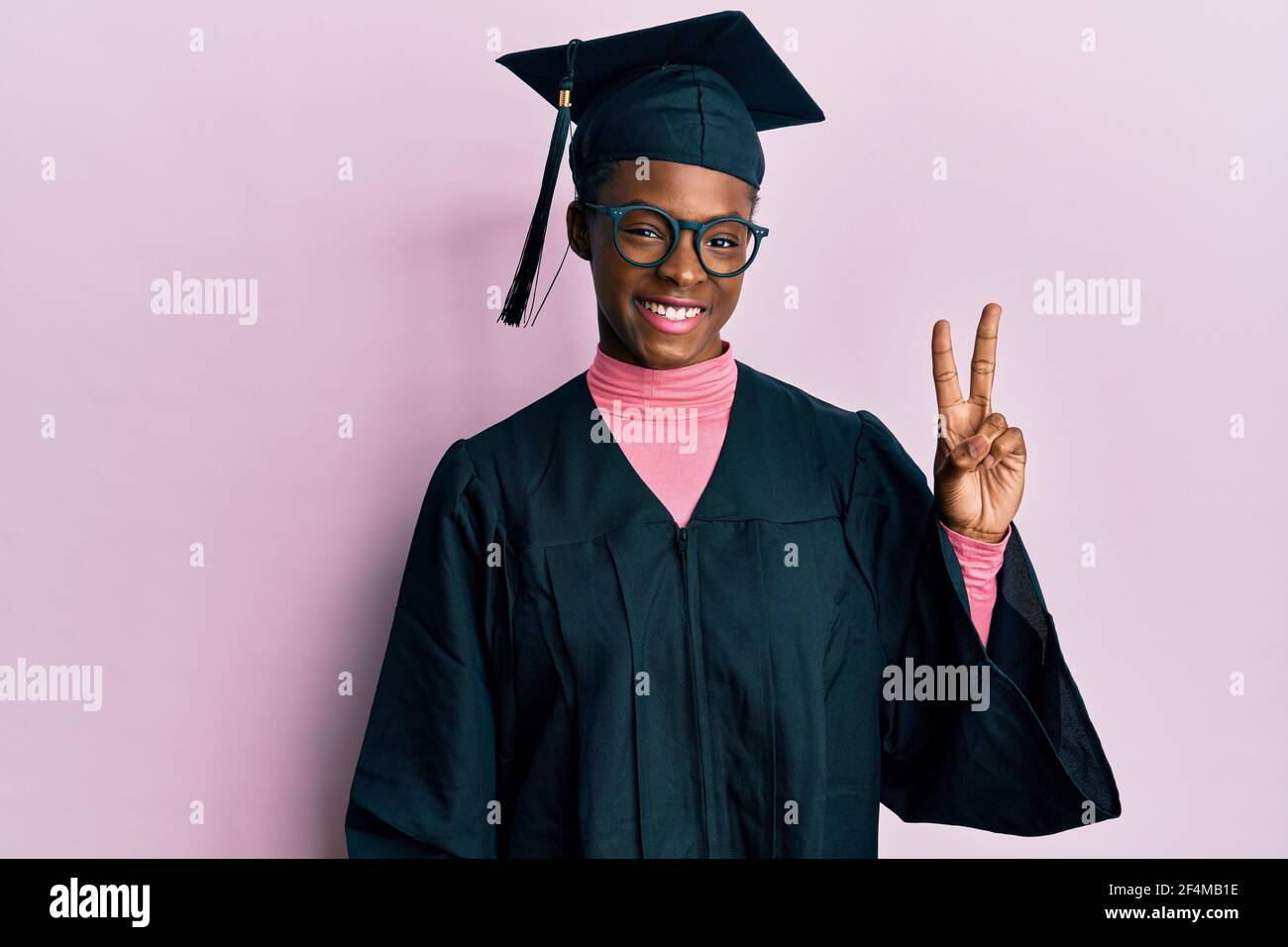 Young african american girl wearing graduation cap and ceremony robe ...
