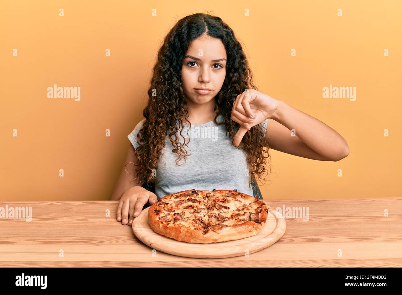 Teenager hispanic girl eating italian pizza with angry face, negative ...