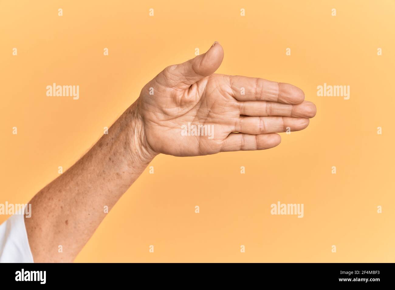 Senior caucasian hand over yellow isolated background stretching and ...