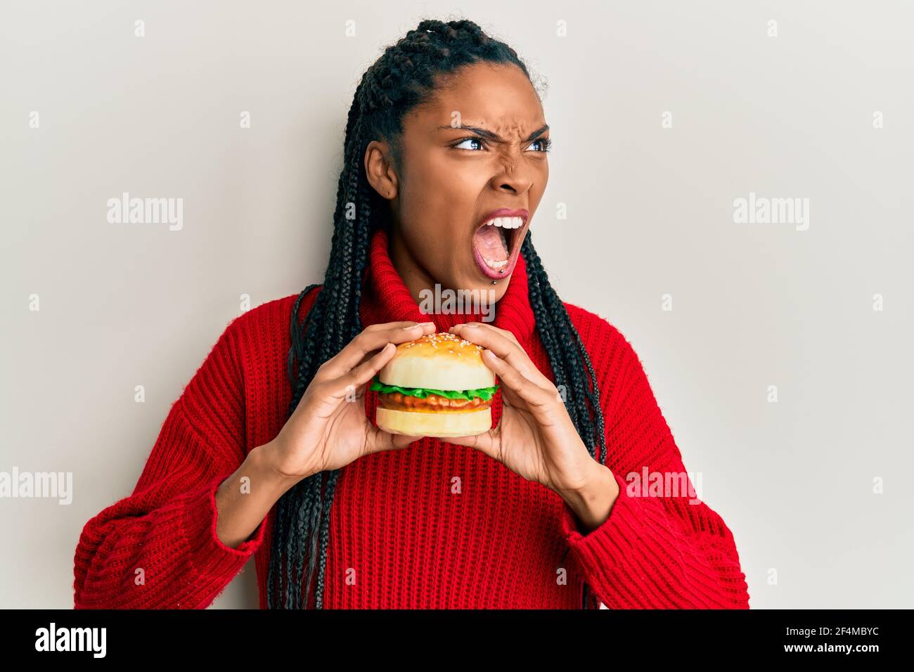 African american woman with braids eating hamburger angry and mad ...