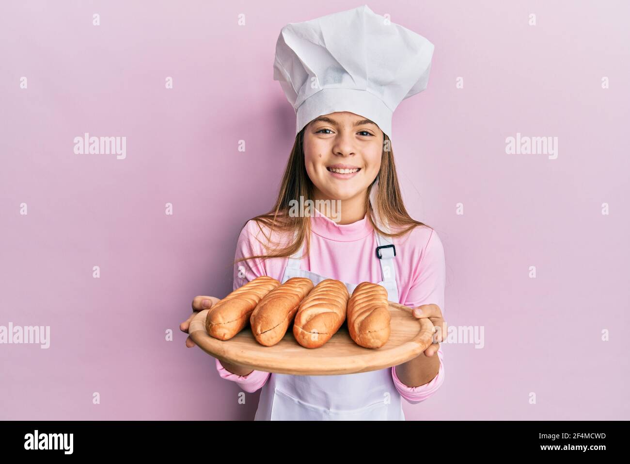 Beautiful brunette little girl wearing baker uniform holding homemade ...