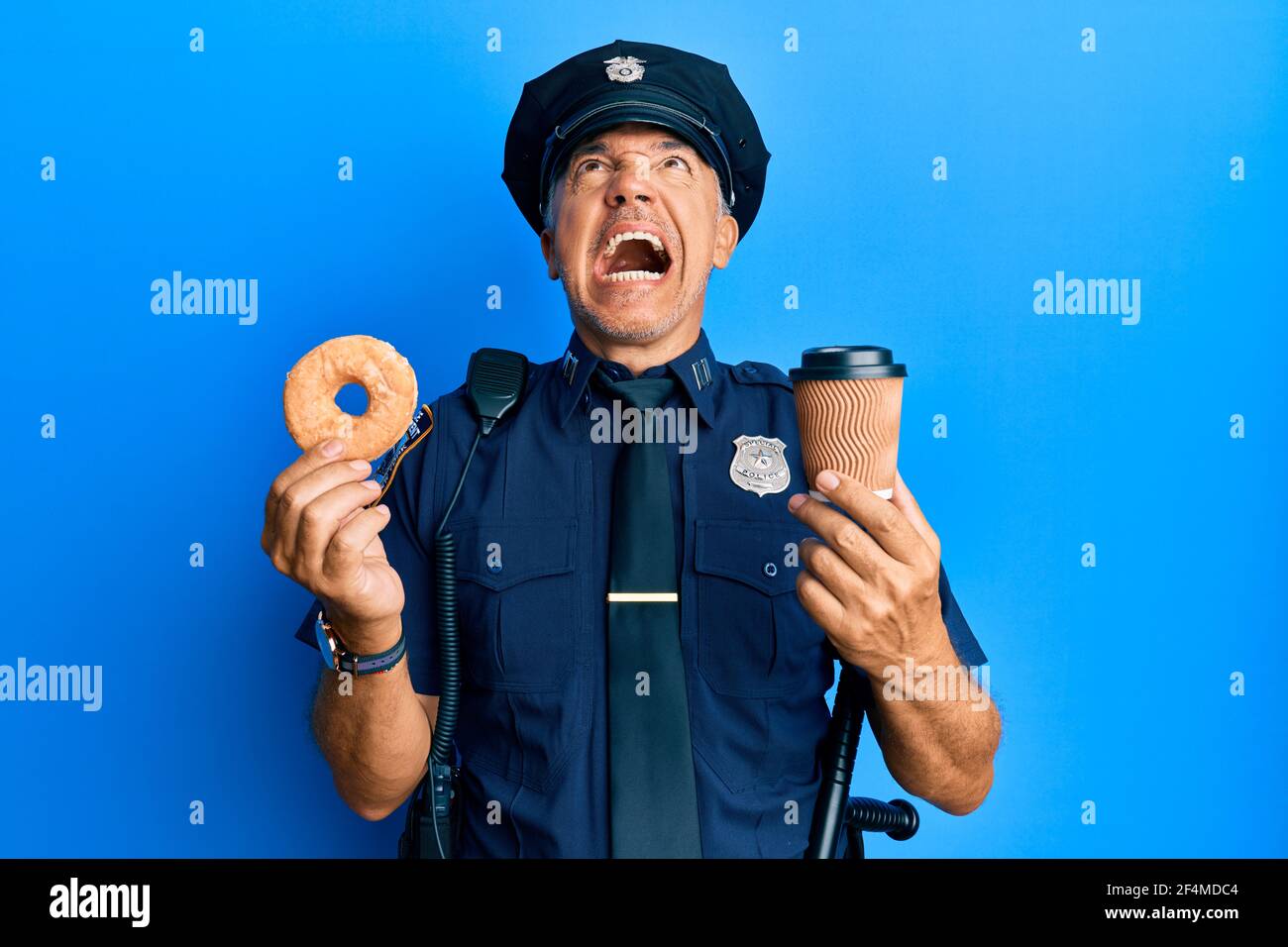 Handsome middle age mature police man eating donut and drinking coffee ...
