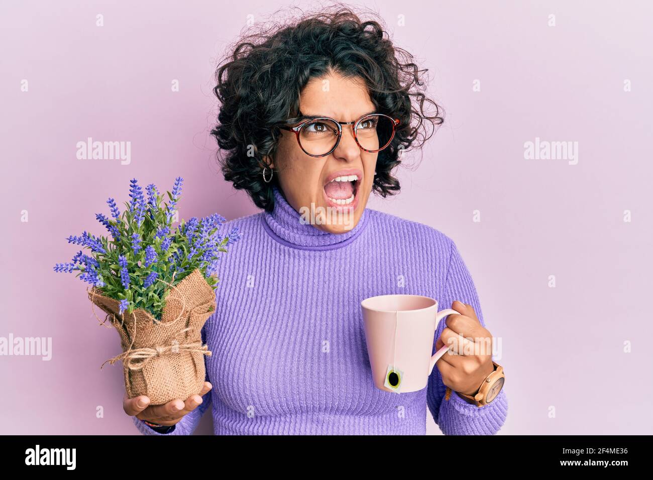 Young hispanic woman with curly hair drinking a cup of infused lavender ...