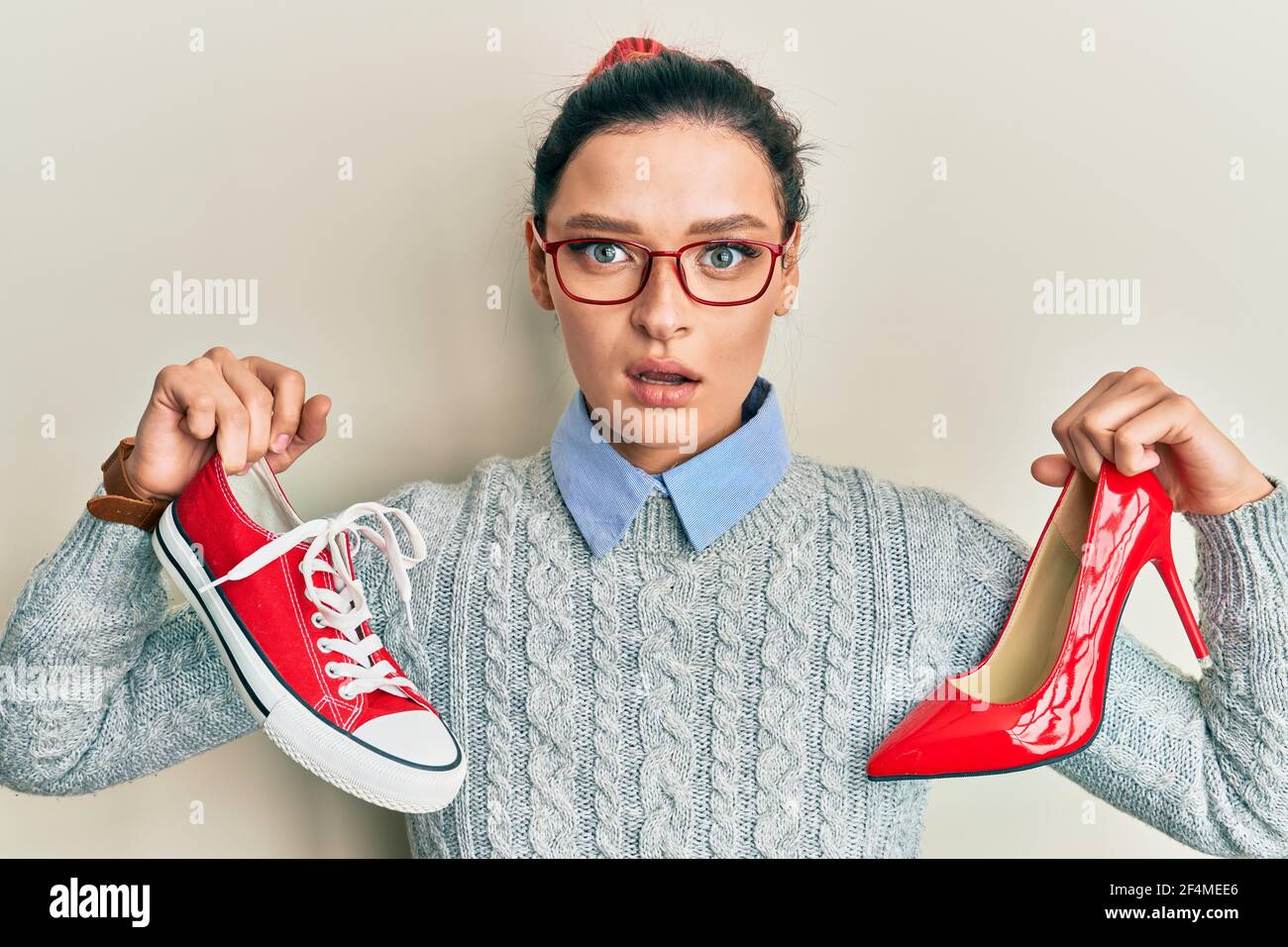 Young caucasian woman choosing high heel shoes and sneakers clueless ...