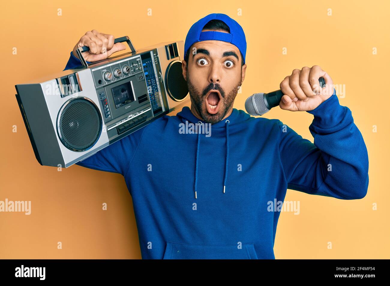 Young hispanic man holding boombox, listening to music singing with ...