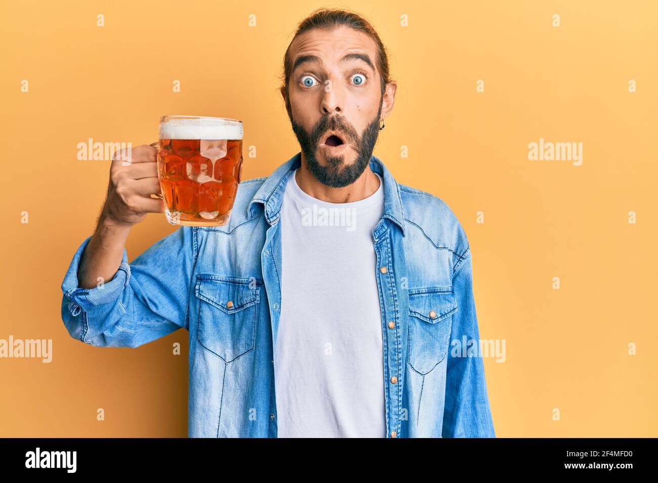 Attractive man with long hair and beard drinking a pint of beer scared ...
