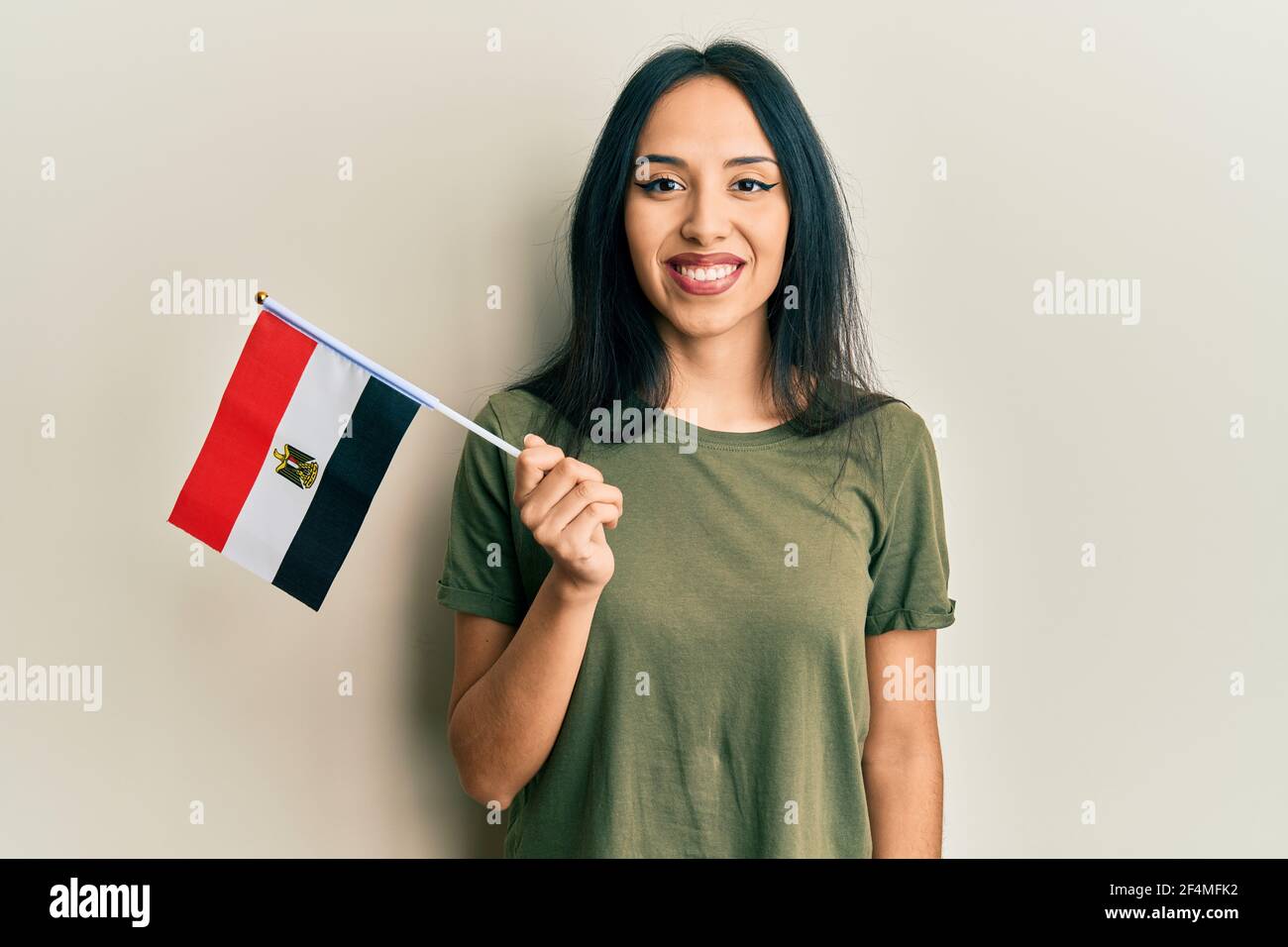 Young hispanic girl holding egypt flag looking positive and happy ...