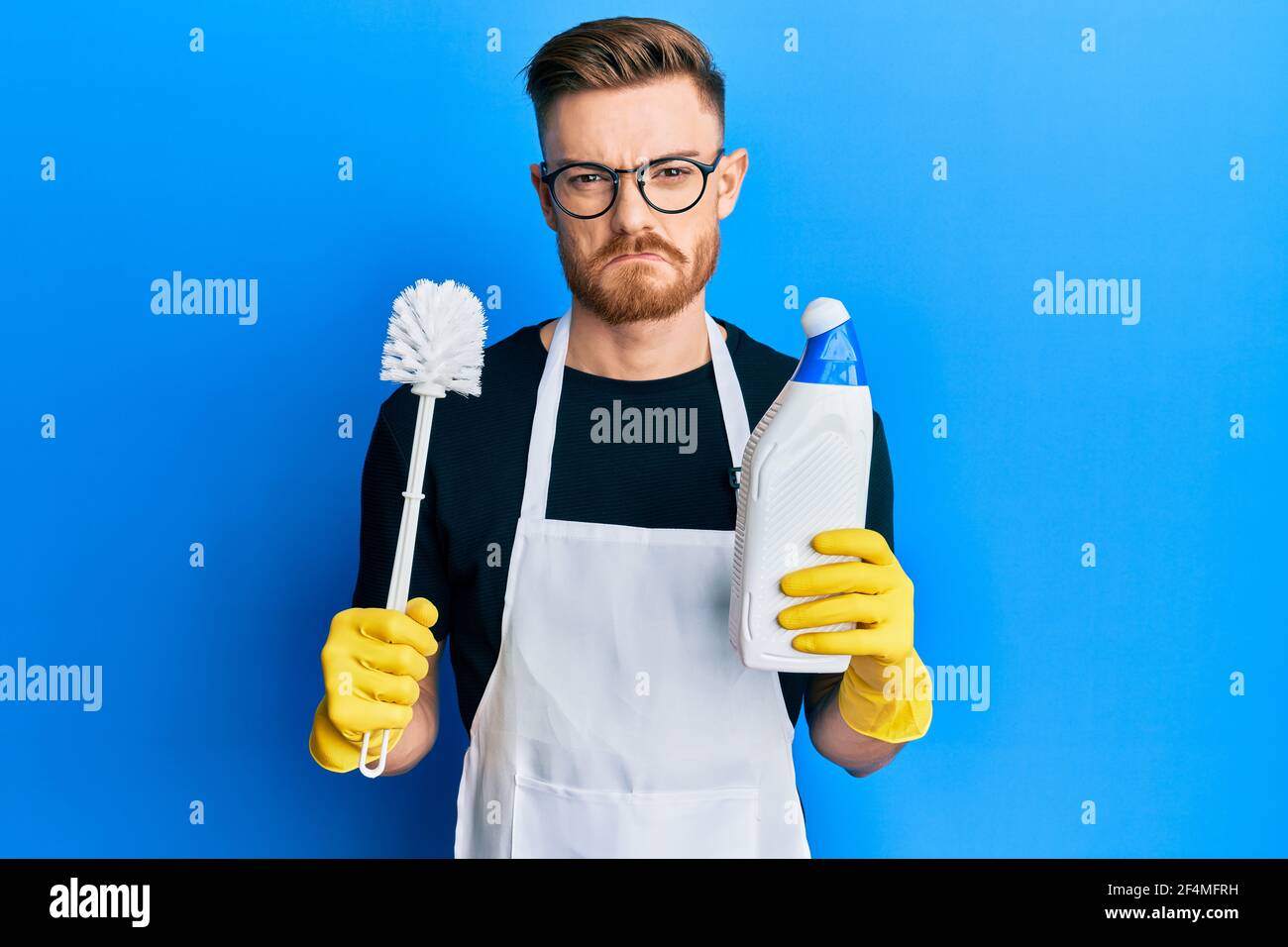 Young redhead man doing bathroom housework with toilet brush depressed ...