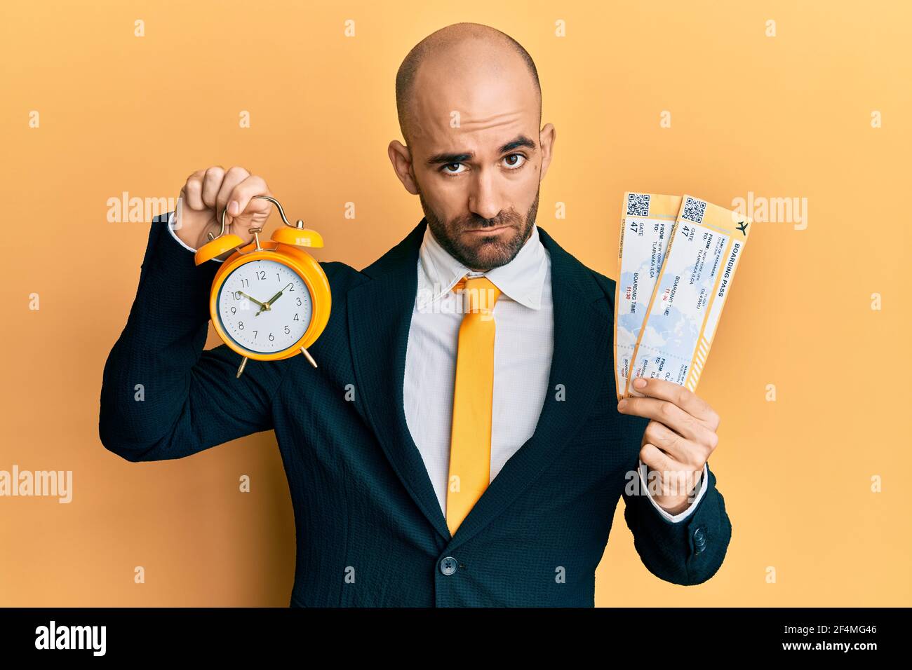 Young hispanic business man holding boarding pass and alarm clock ...