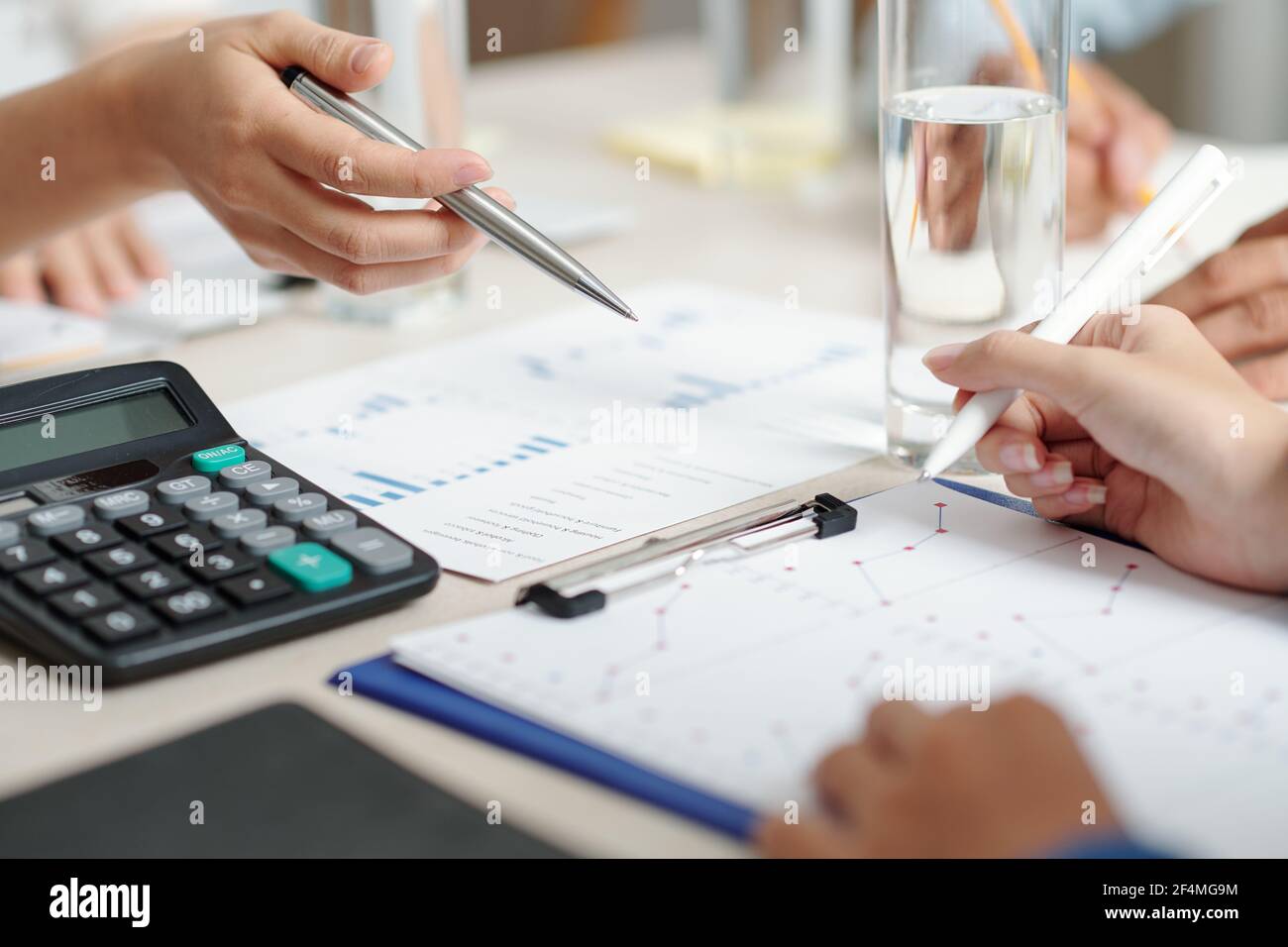 Business people working with charts and reports and talking about key ...