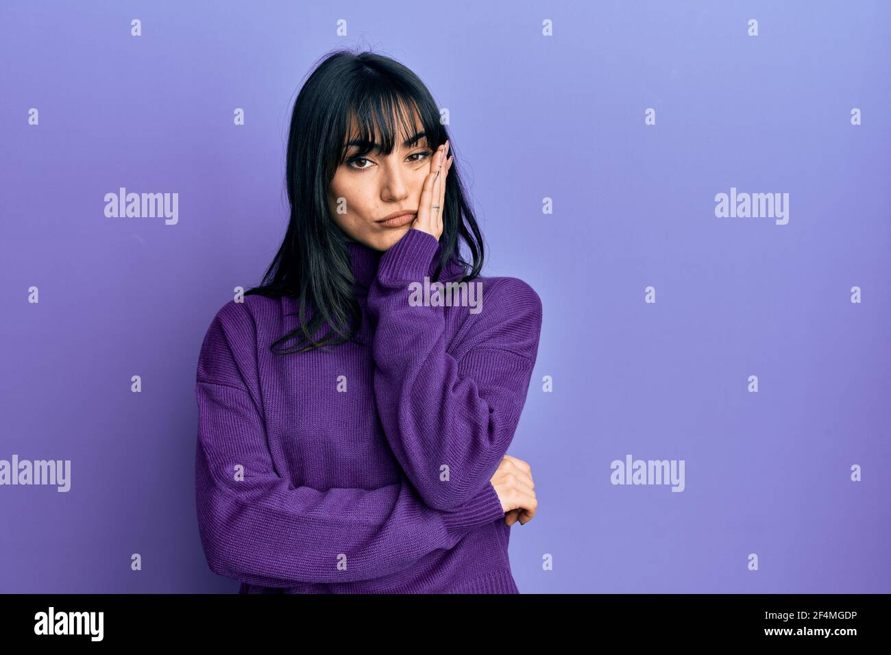 Young brunette woman with bangs wearing turtleneck sweater thinking ...