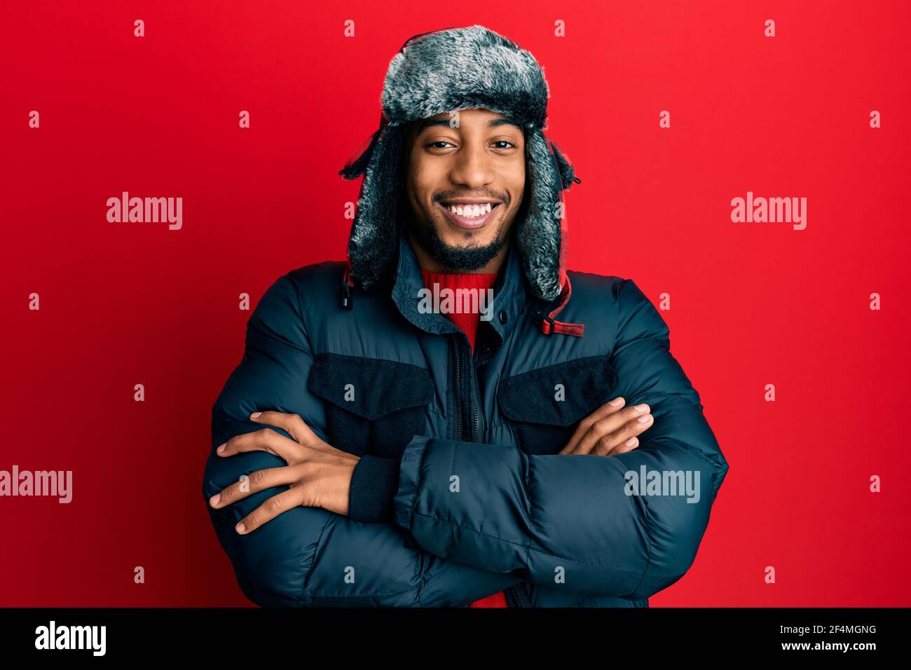 Young african american man with beard wearing winter hat and coat happy ...