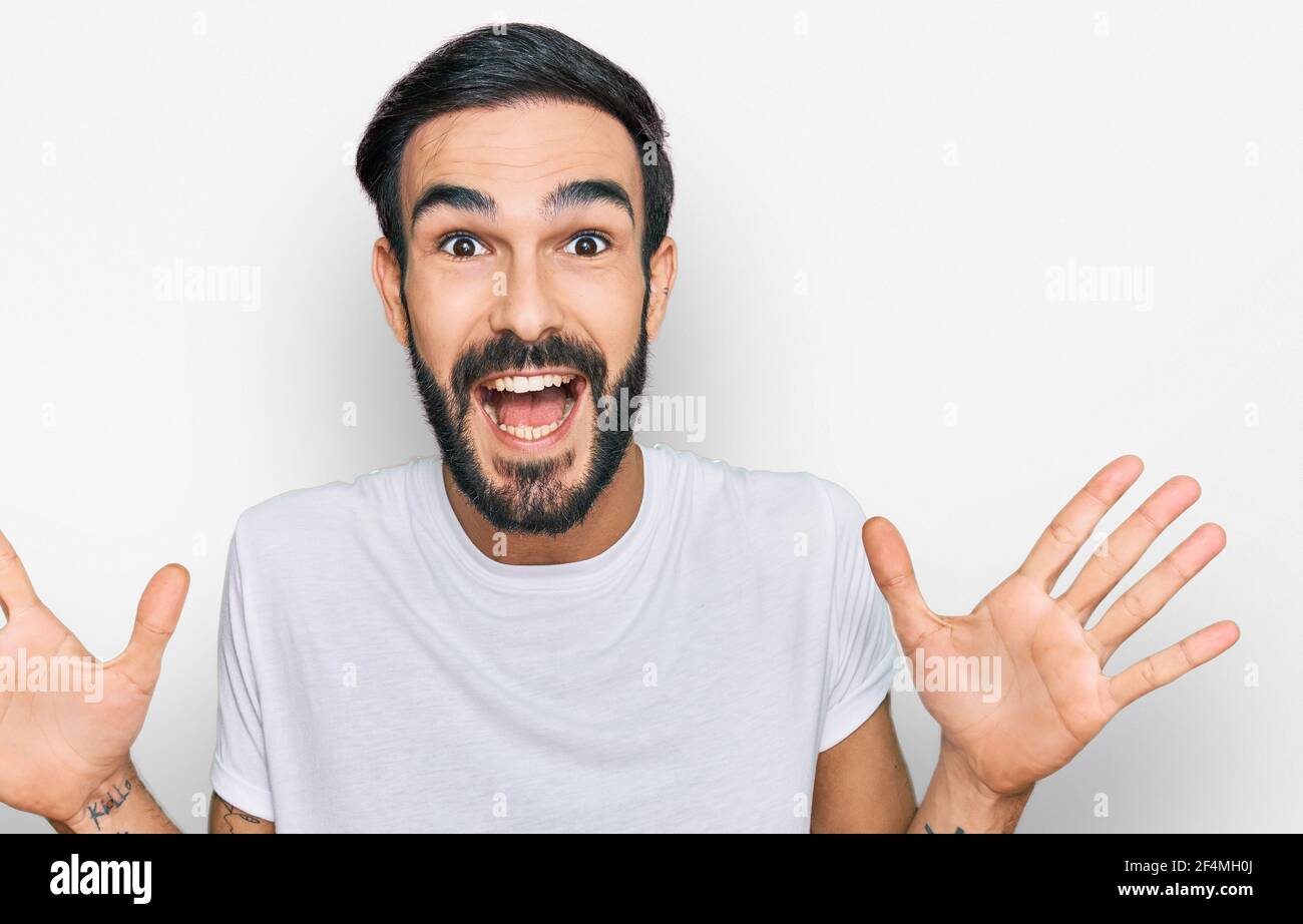 Young hispanic man wearing casual white t shirt celebrating crazy and ...