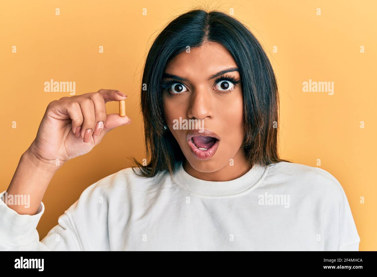 Young latin transsexual transgender woman holding pill scared and ...