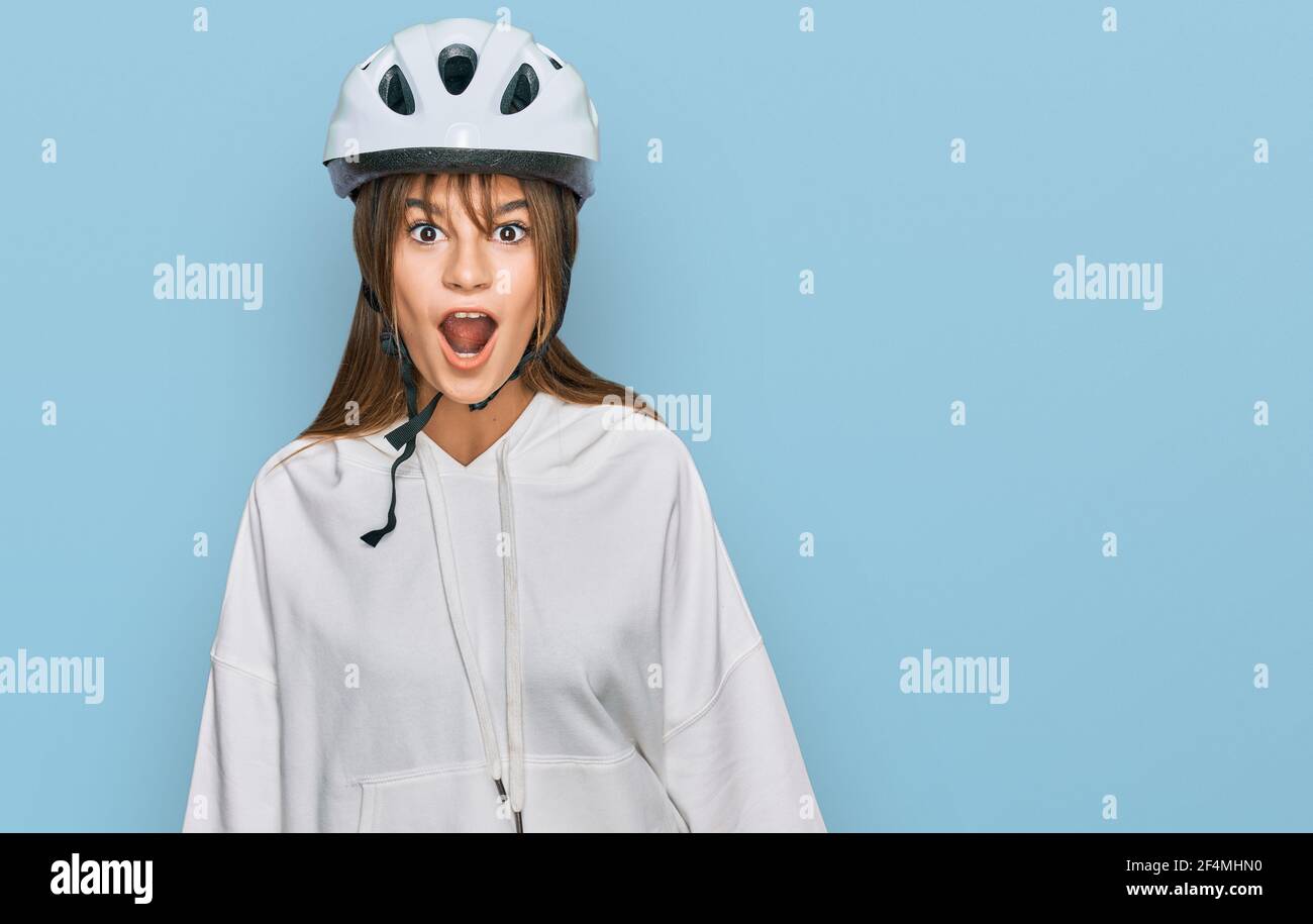 Teenager caucasian girl wearing bike helmet afraid and shocked with ...
