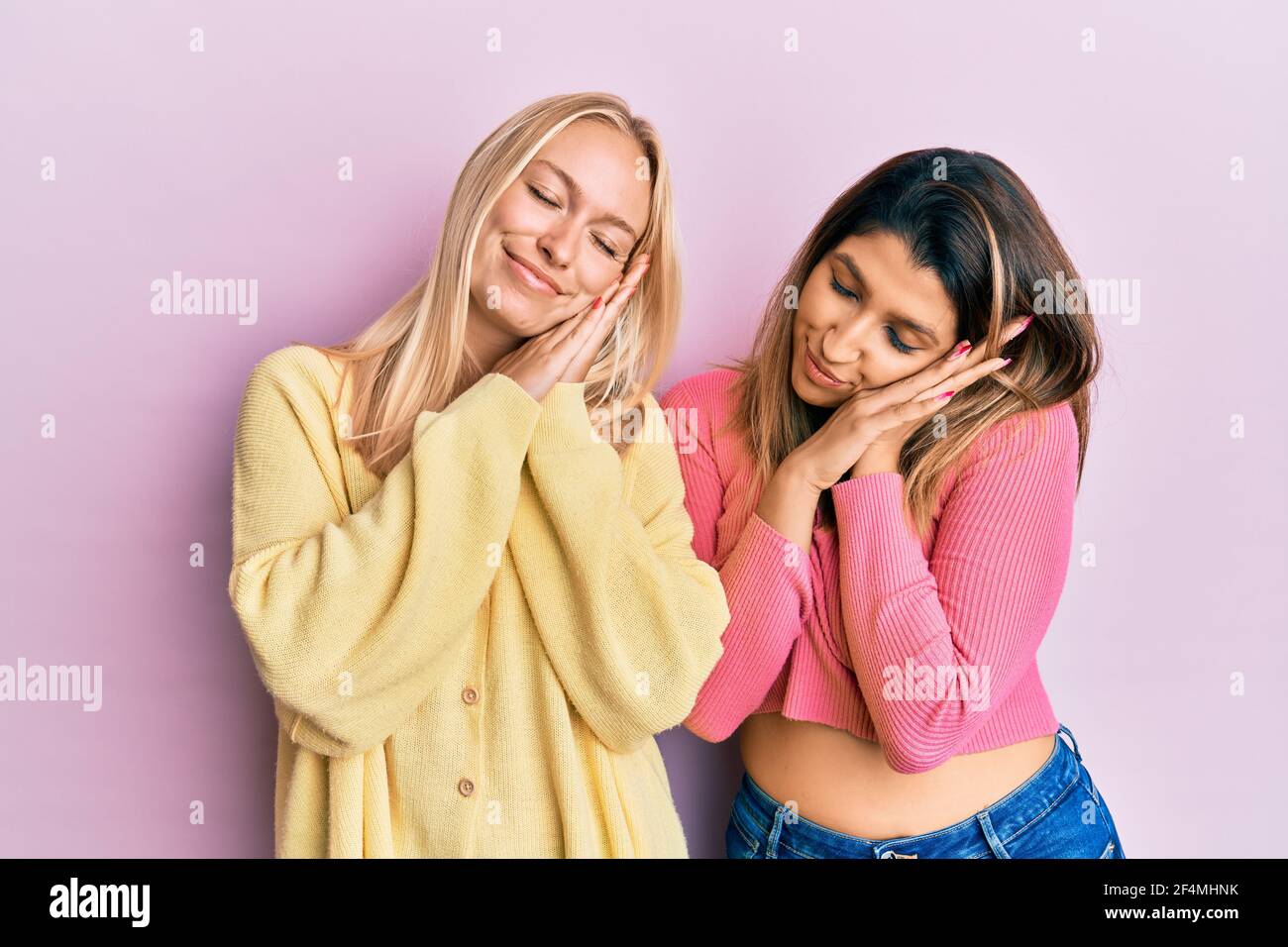 Two friends standing together over pink background sleeping tired ...
