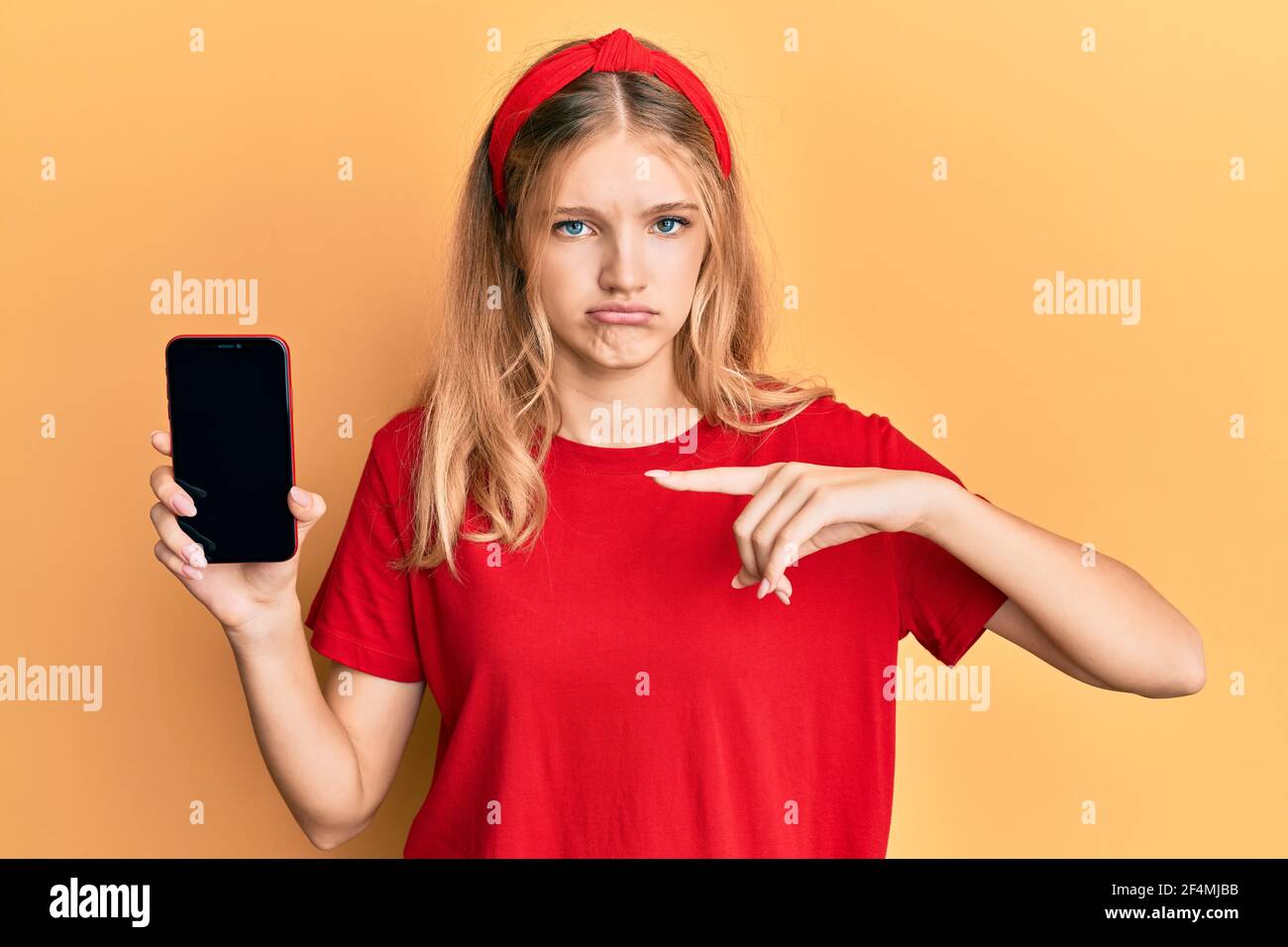 Beautiful young caucasian girl holding smartphone showing screen ...