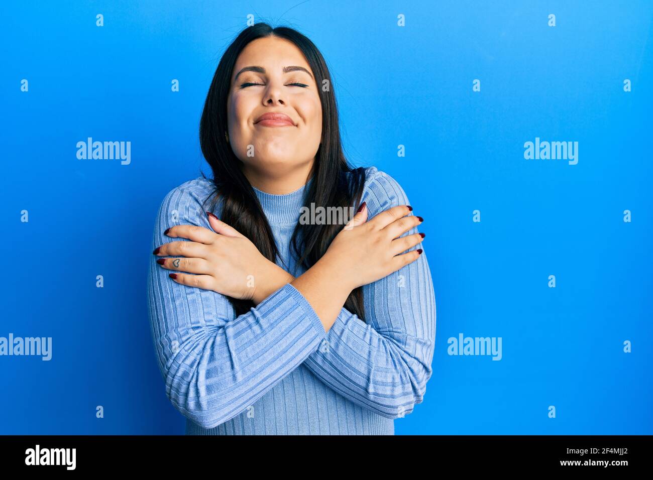 Beautiful brunette woman wearing casual clothes hugging oneself happy ...