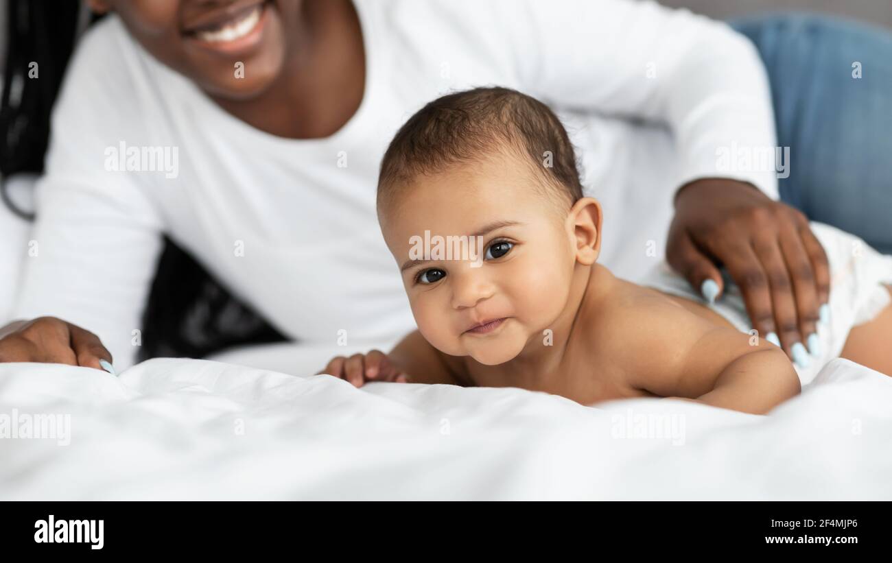 Cute little African American baby crawling in bed with mom Stock Photo ...