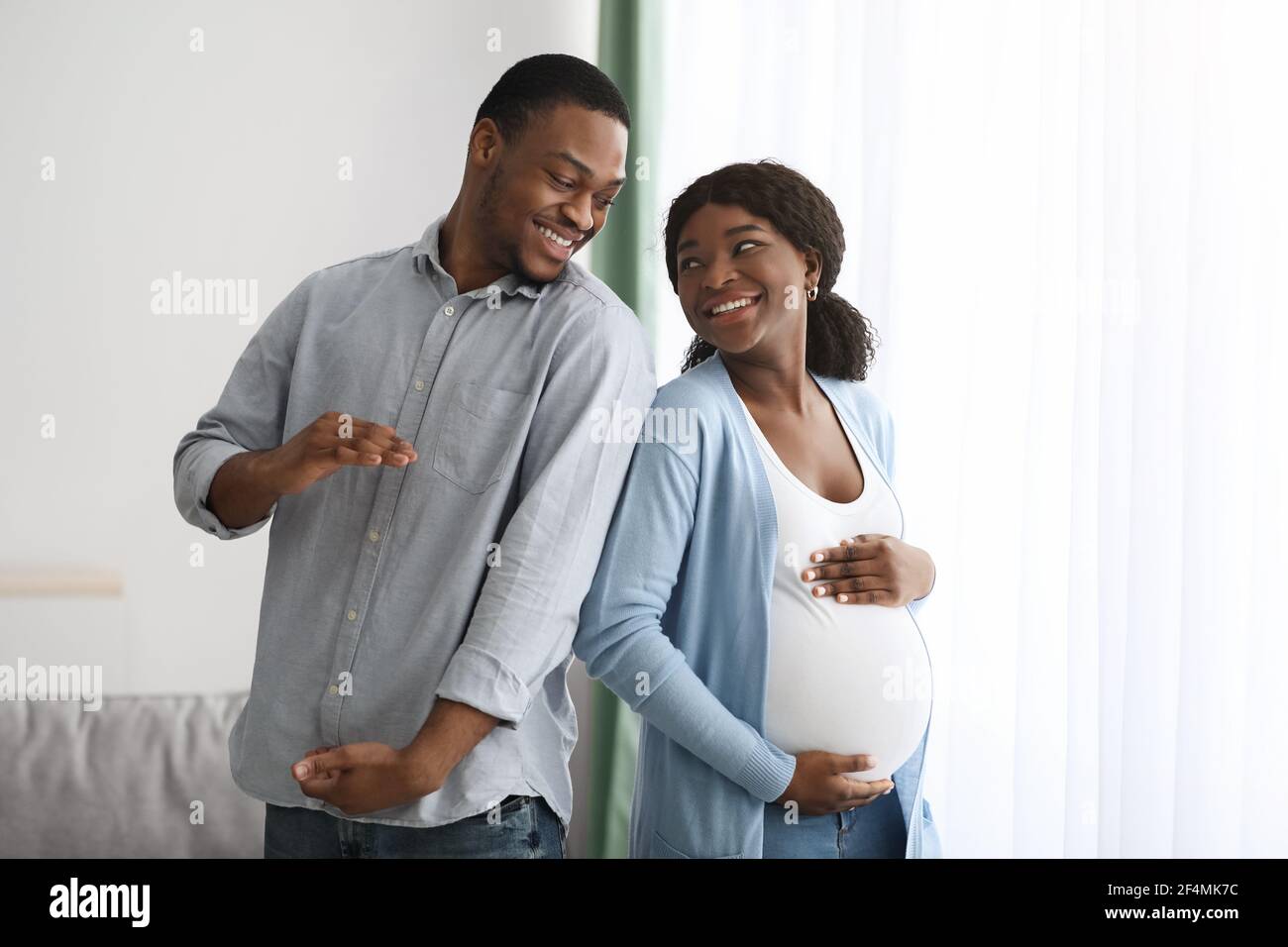 Loving black man imitating his pregnant wife Stock Photo - Alamy