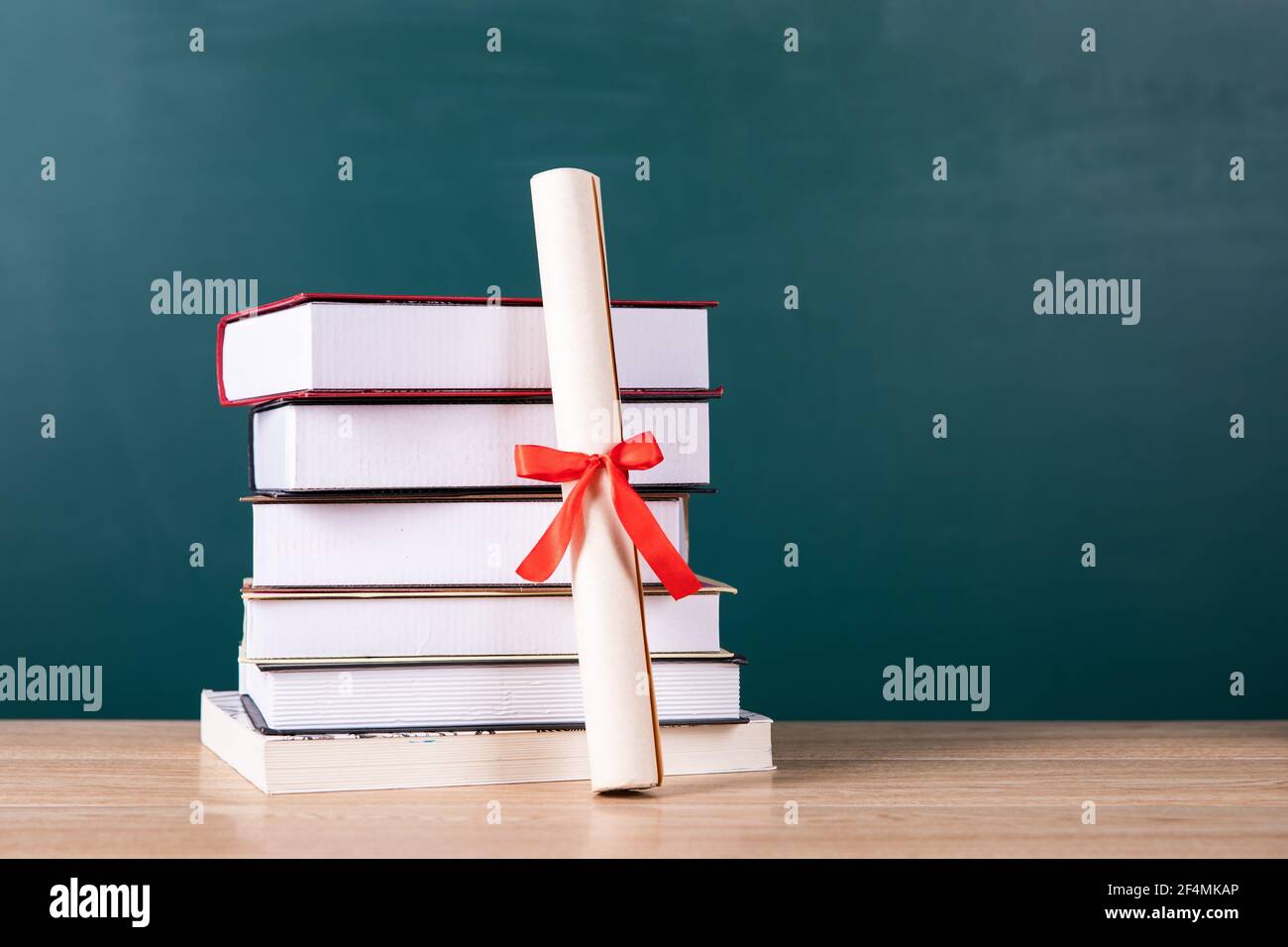 Diploma with a red ribbon and a stack of books on green chalkboard ...