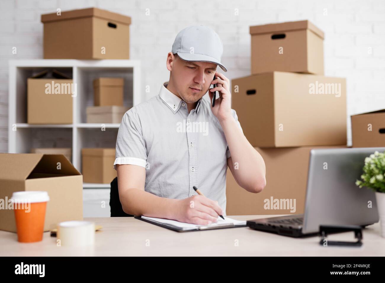 Work and business concept - male postman talking by phone and writing ...