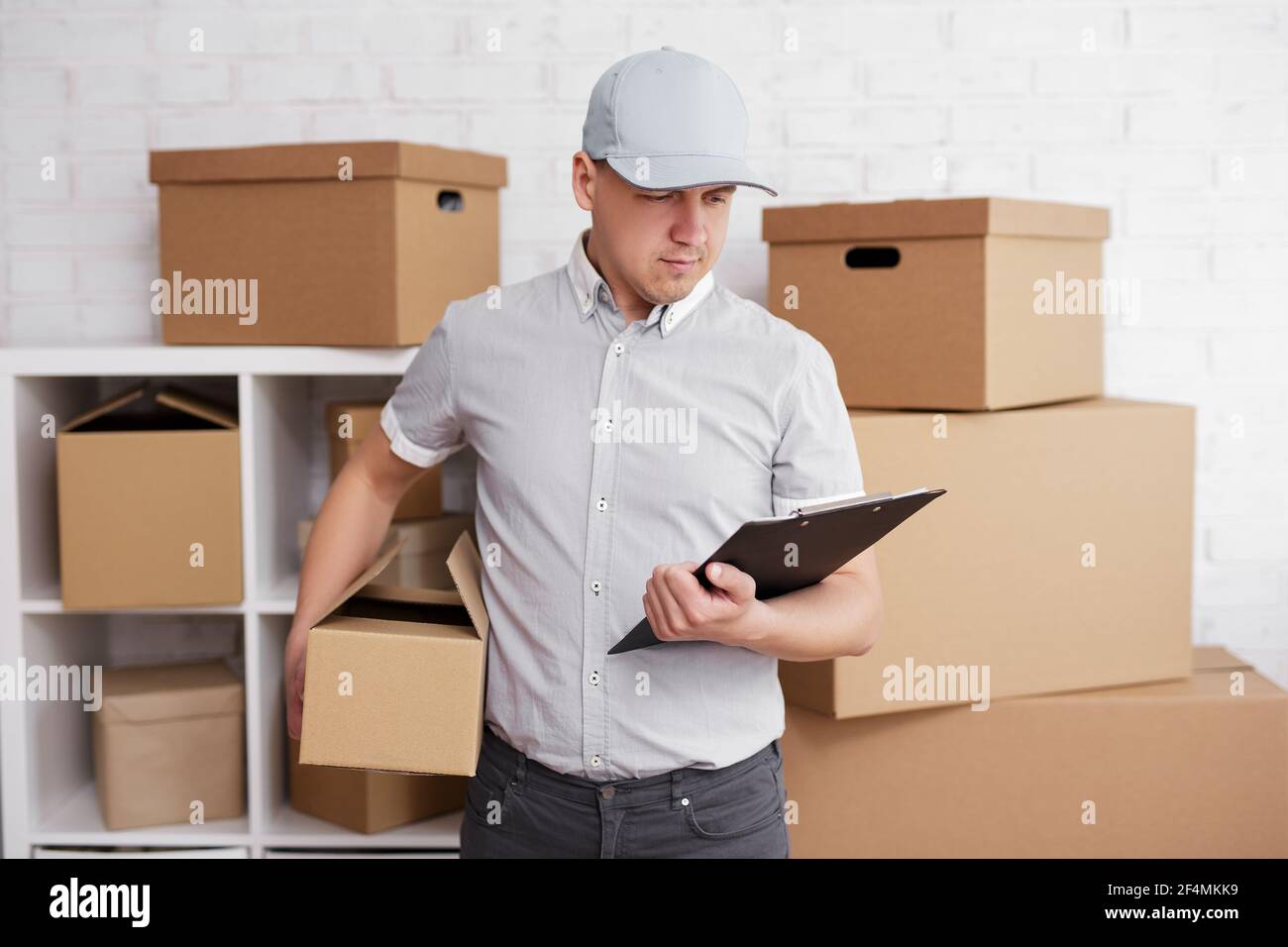 postal delivery - man in warehouse with box and clipboard Stock Photo ...