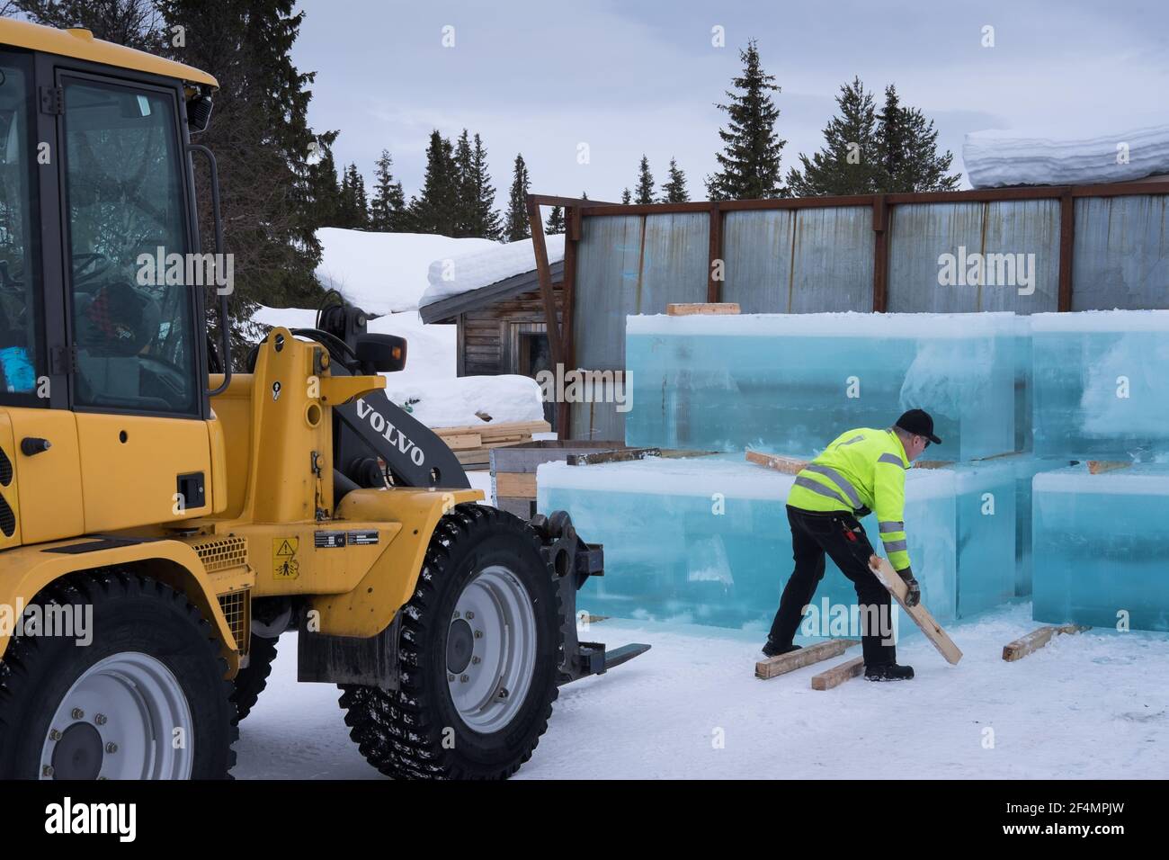 Man stacks rectangular cut ice block from a frozen lake needed to build ...