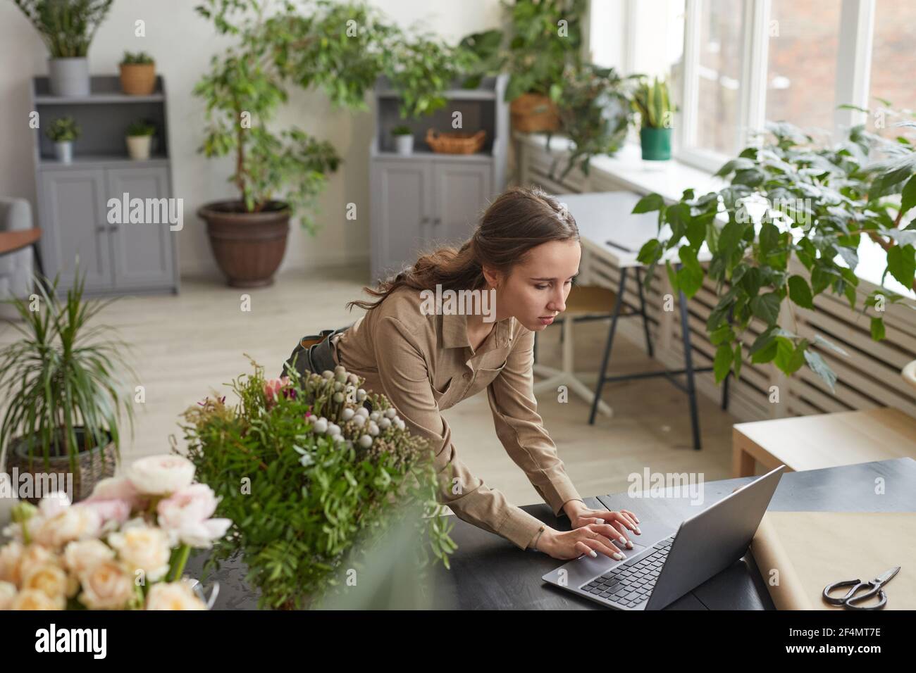High angle portrait of young female florist using laptop while managing ...