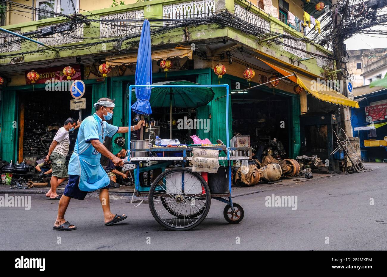 A male food pushes his food cart along the road in the Talat Noi area ...