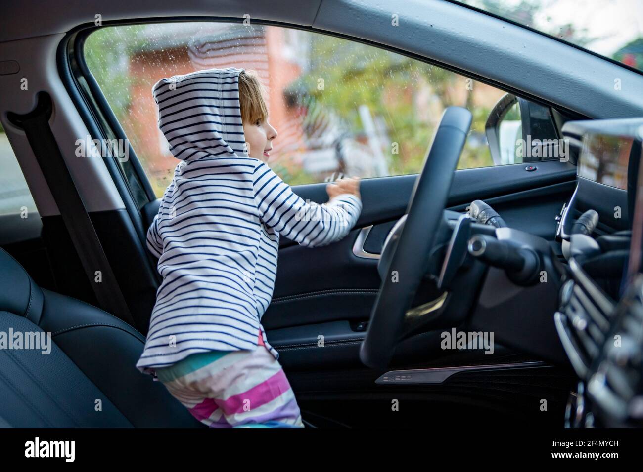 adorable toddler child plays driving on drivers seat of modern premium ...