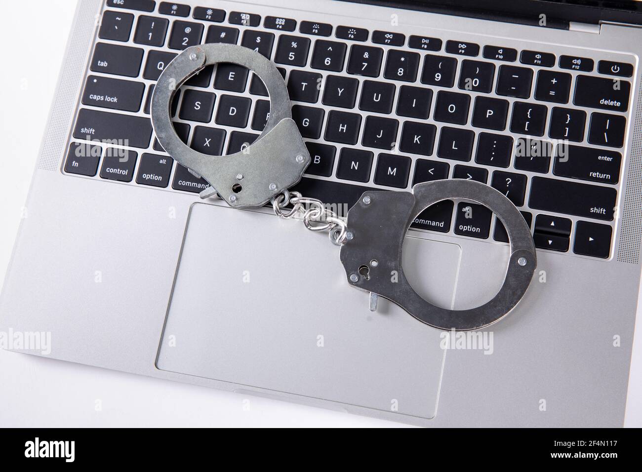 Closeup shot of handcuffs lying on laptop keypad - online crime concept ...