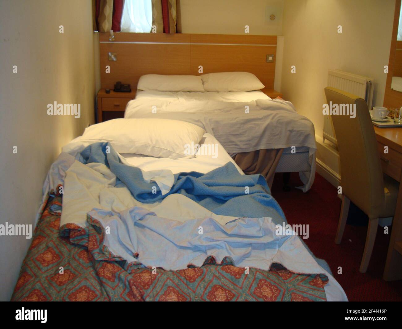tow untidy unmade beds squashed into a small dark room Stock Photo - Alamy