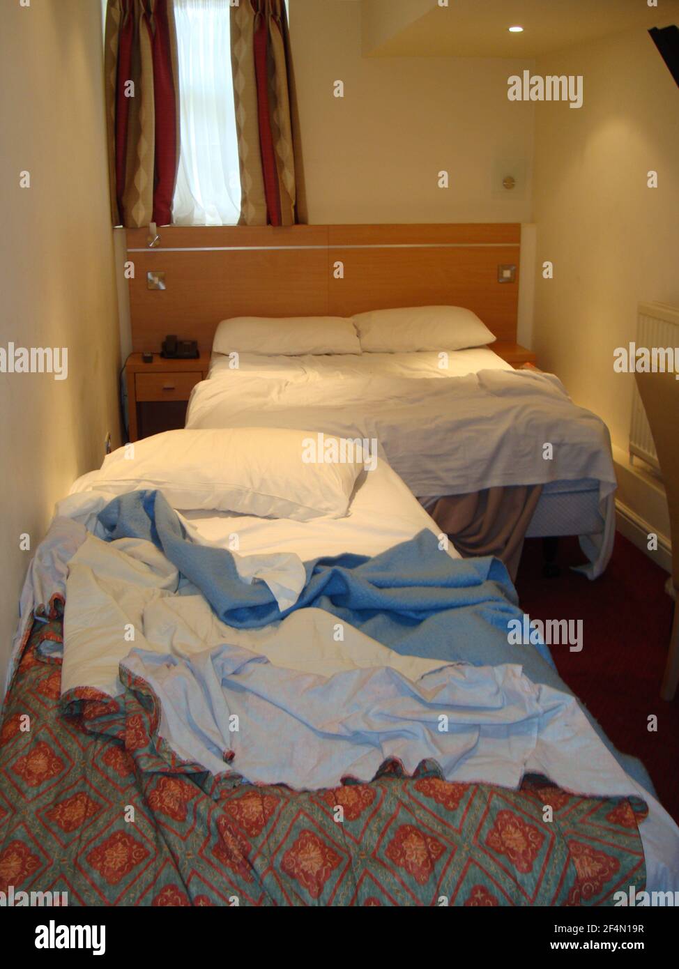 tow untidy unmade beds squashed into a small dark room Stock Photo - Alamy