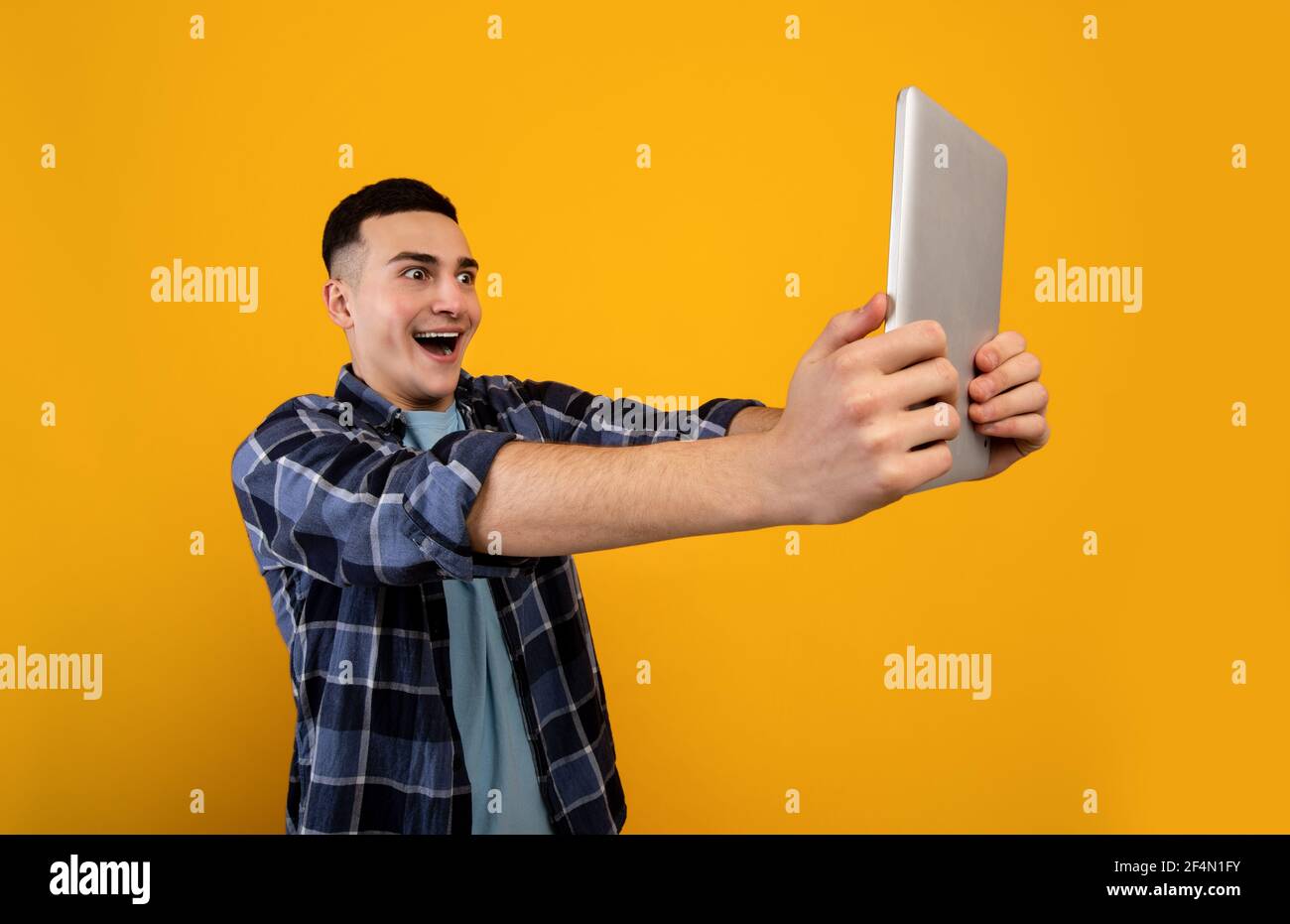 Shocked young guy looking at tablet screen in surprise, reading ...