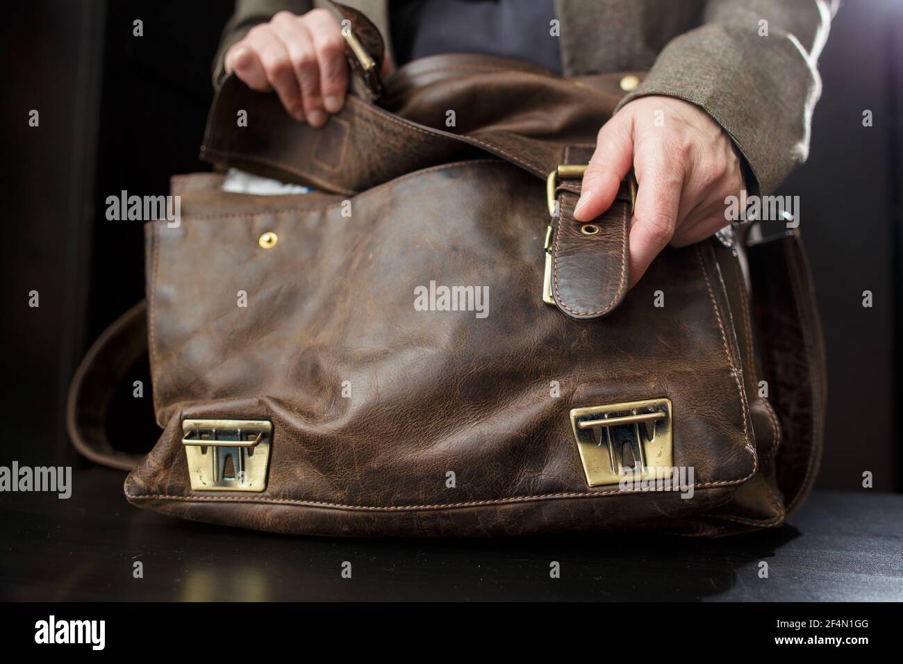 Hands professor open buckle on the old leather briefcase, before class ...
