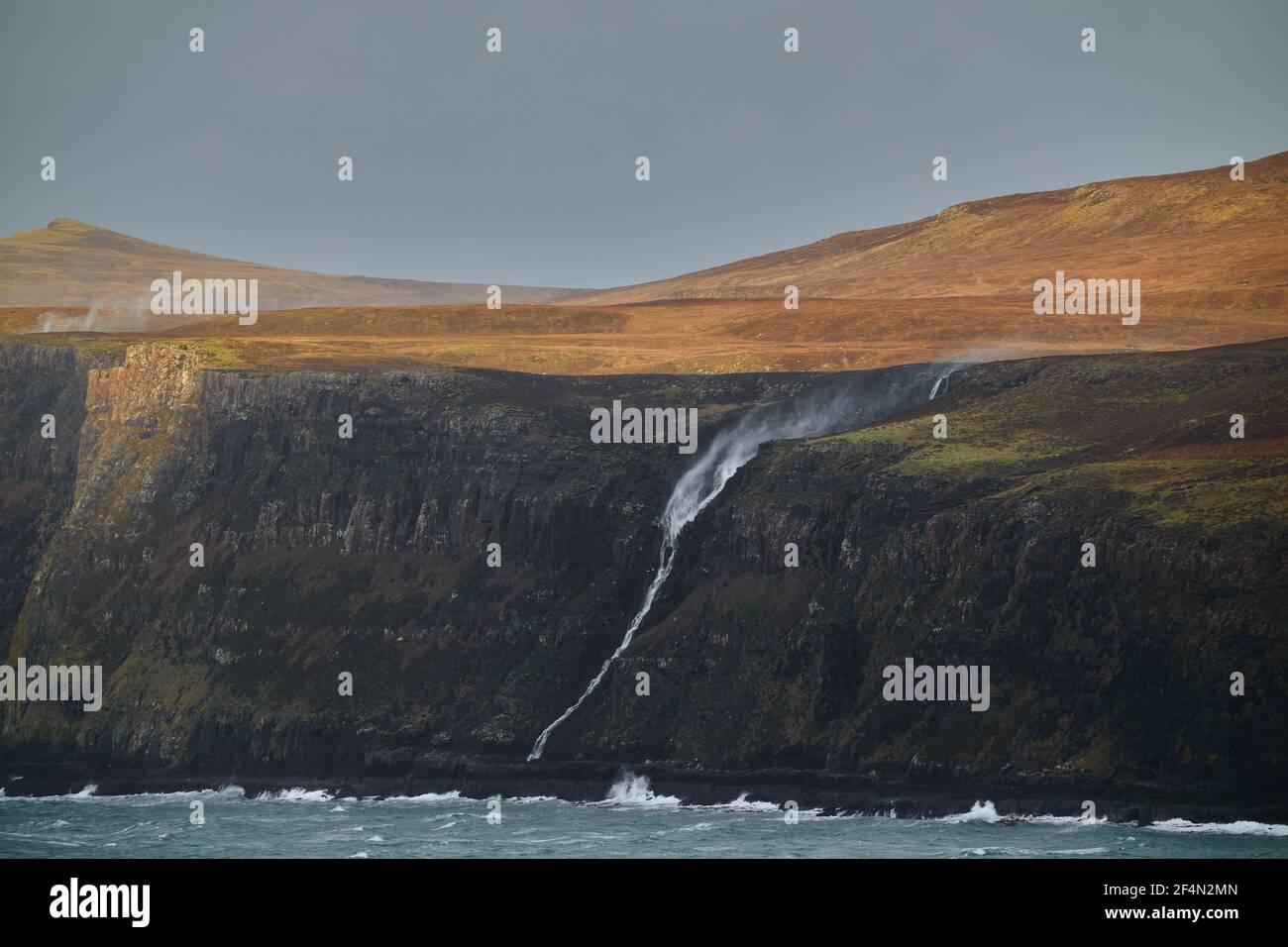 waterfall on cliff in windy day with spray of water going back towards ...