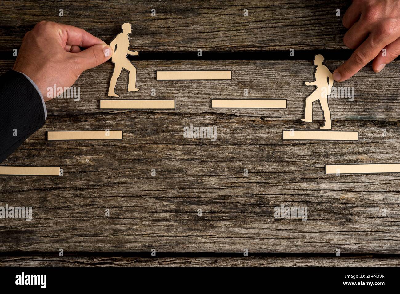 Two paper cutout men striving for the same goal climbing steps in ...