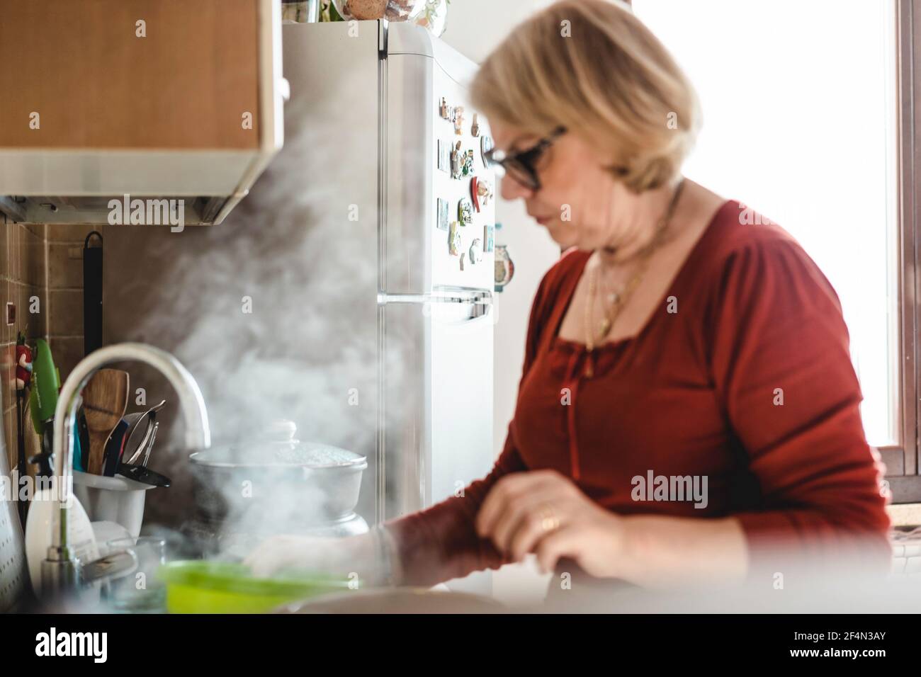 Senior woman cooking lunch in the kitchen - Mature woman in the kitchen ...