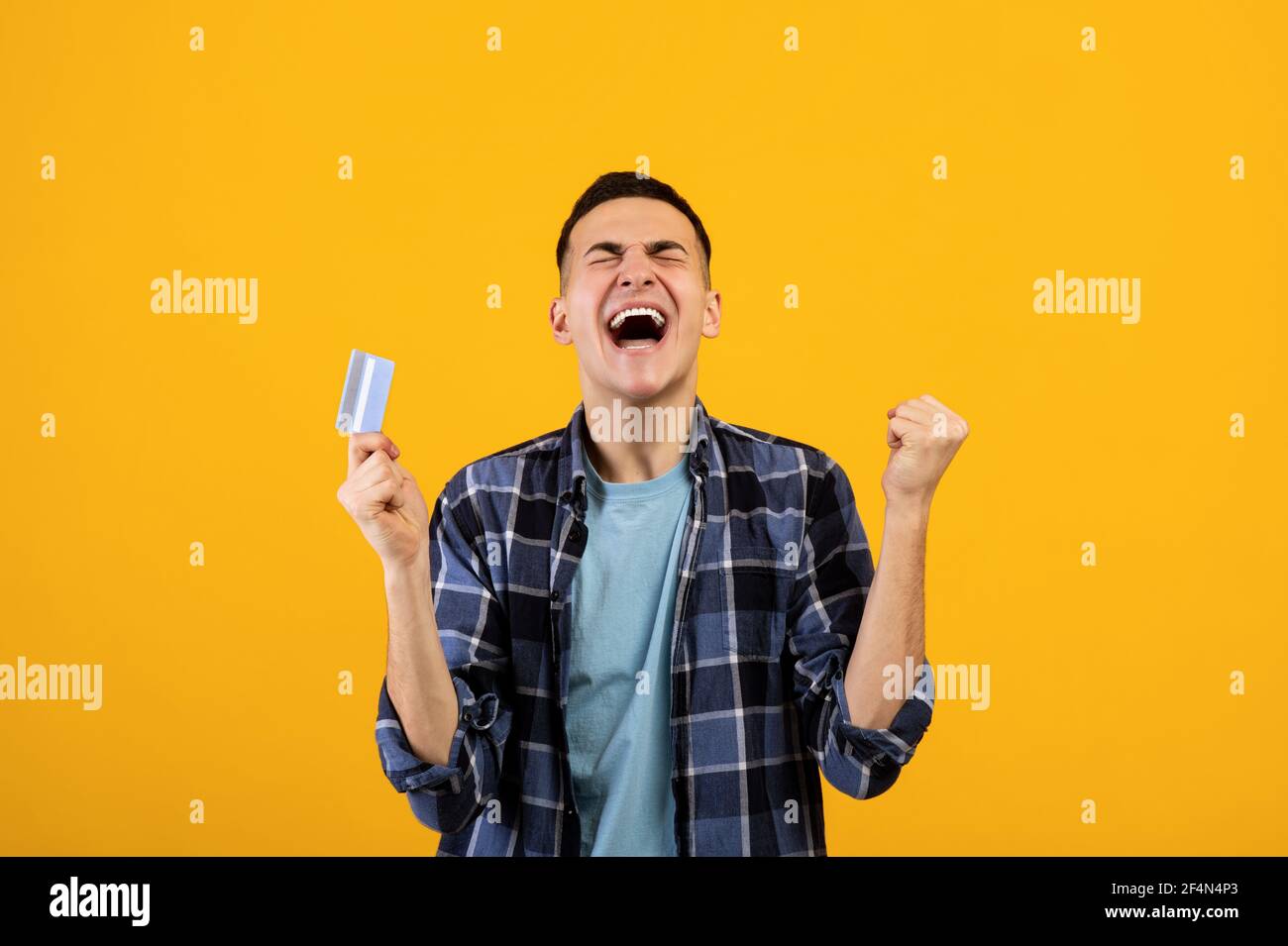 Excited young guy with credit card screaming OMG and making YES gesture ...