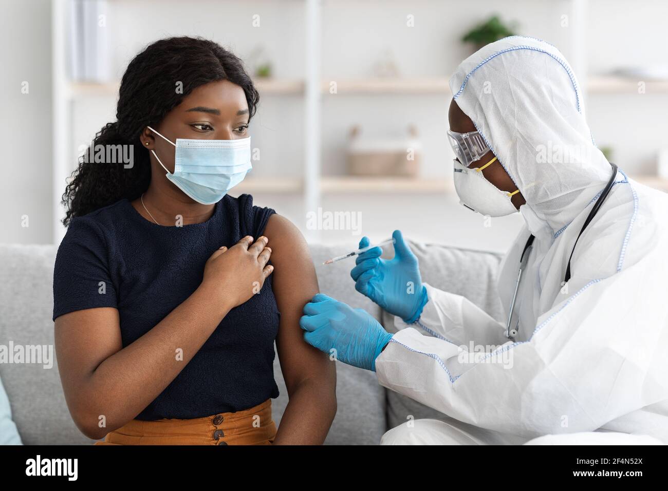 Black woman in face mask getting injection at home Stock Photo - Alamy