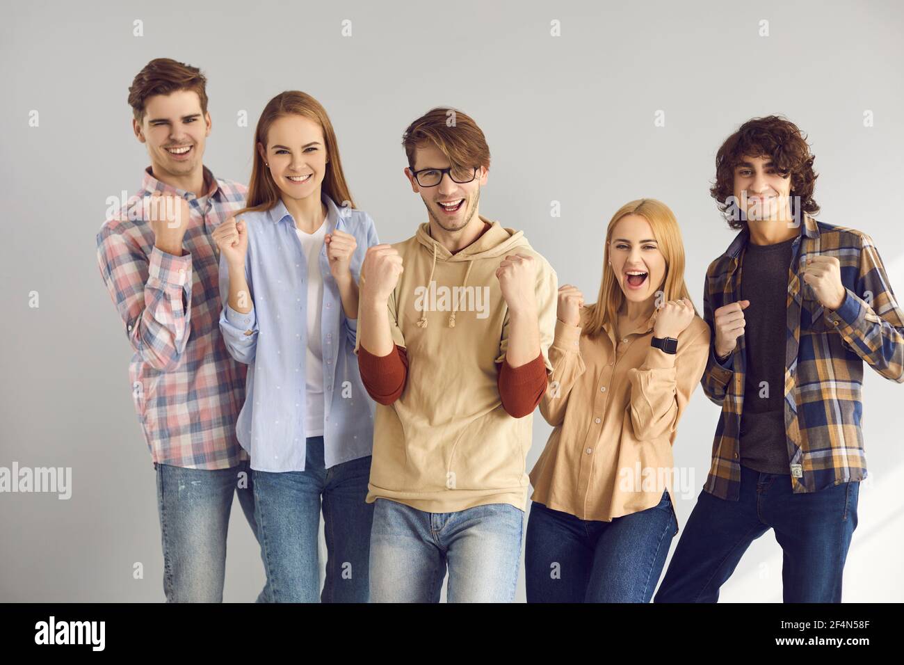 Group of excited young people celebrating achieving goals, fist pumping ...