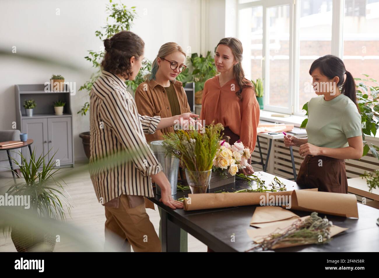 Wide angle view at diverse group of young florists arranging floral ...