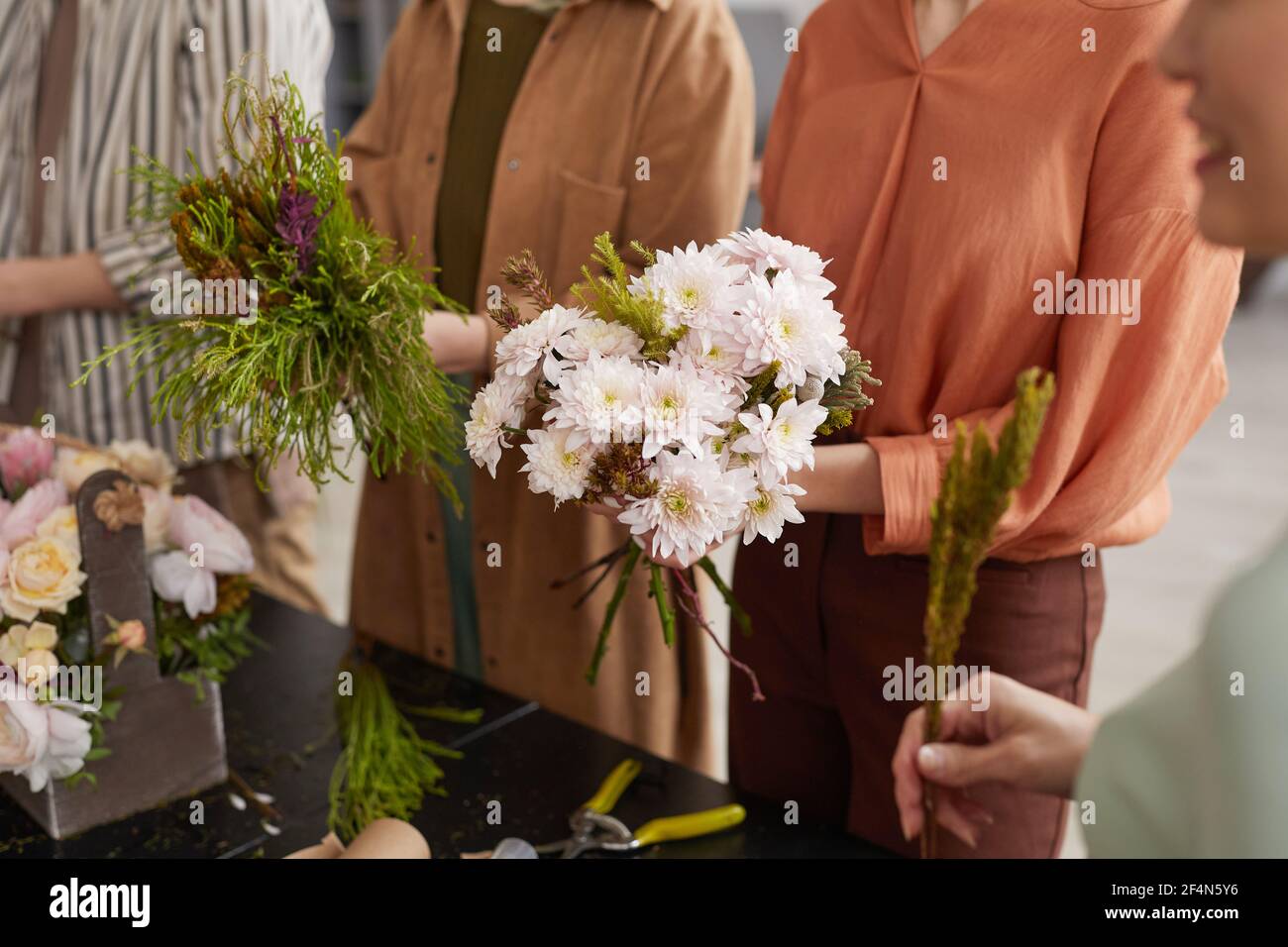 Close up of diverse group of young people attending class on floral art ...